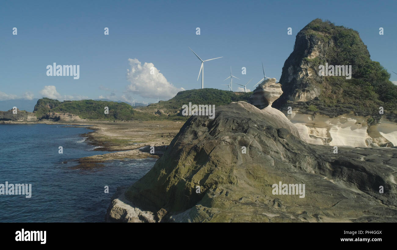 Natural rock formation of limestone stone on the coast with windmills ...