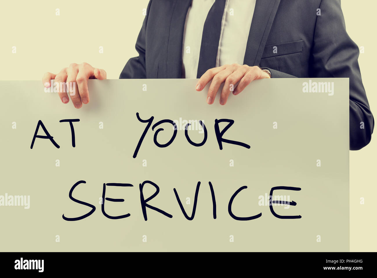Businessman holding white signboard with Aty your service sign ...