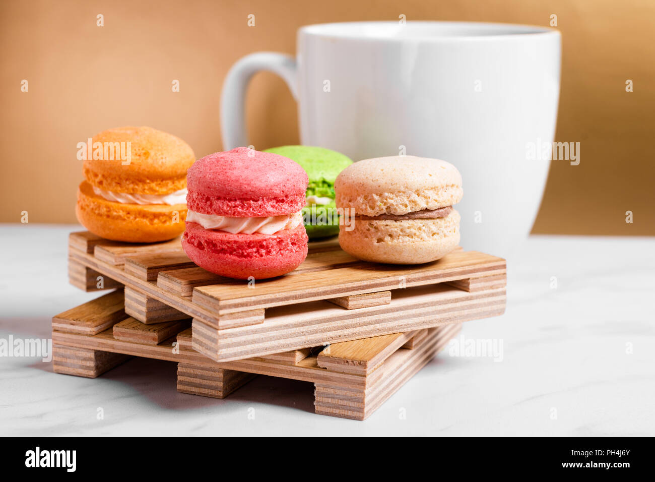 Sweet and colourful macaroons served on little wooden pallets with cup ...
