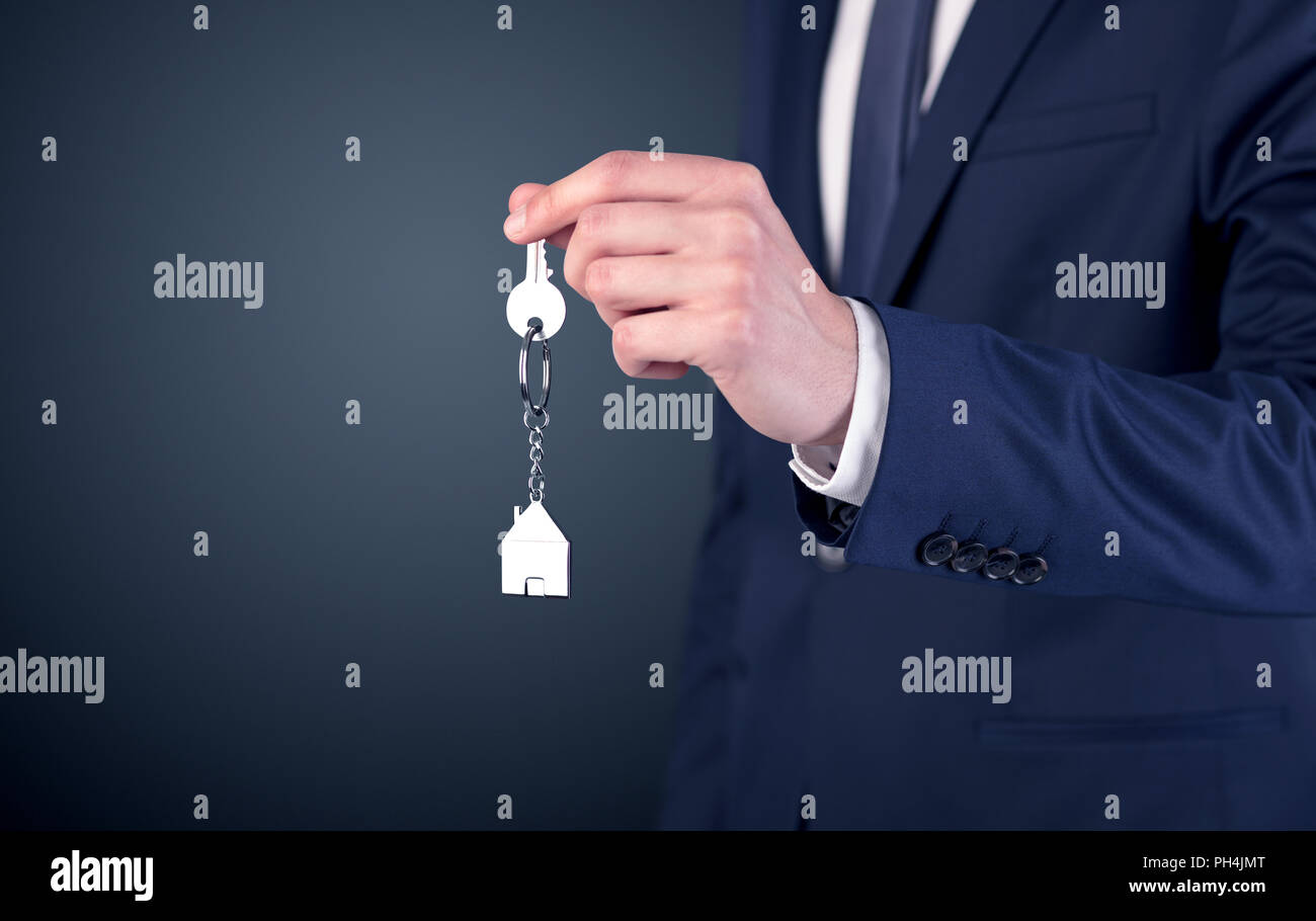 Young businessman hand over keys with empty dark background Stock Photo ...