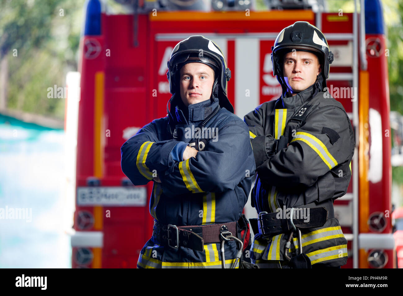 Photo of two young firemen with hands on waist near fire engine Stock ...