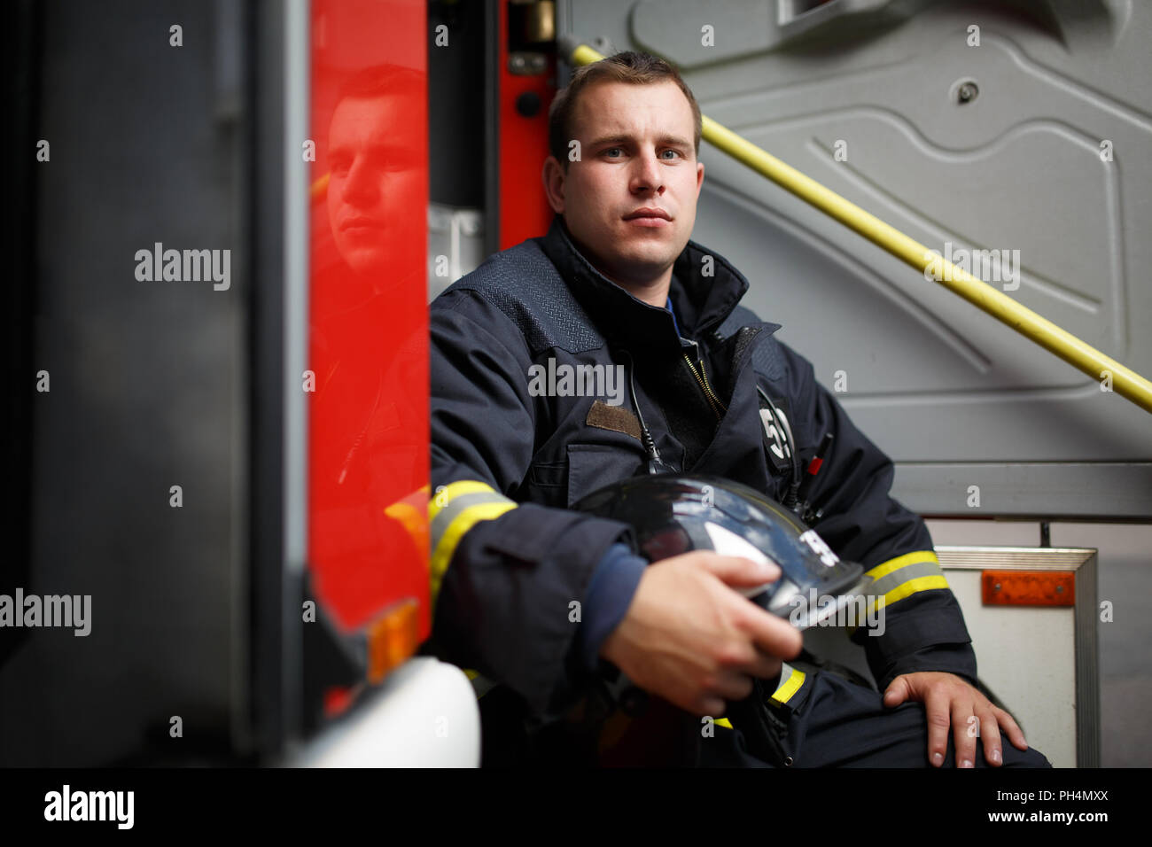 Photo of fireman with helmet in hands sitting in fire engine Stock ...