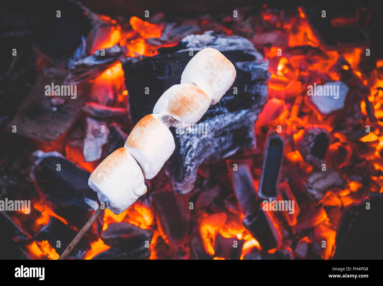 Set of sweet marshmallows roasting over red fire flames. Marshmallow on ...