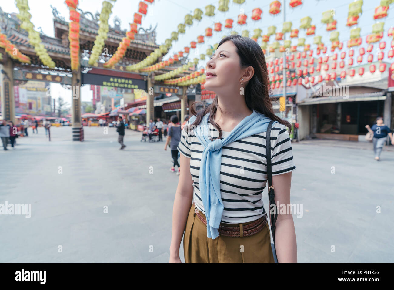 asian woman smiling and looking upward. by the background of temple and ...