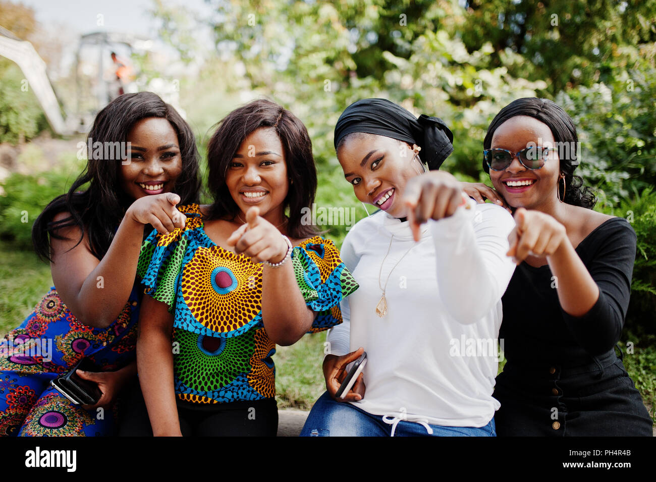 Group of four african american girls sitting outdoor and showing ...
