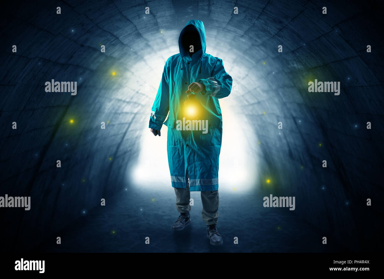 Ugly man in raincoat walking with glowing lantern in a dark tunnel ...