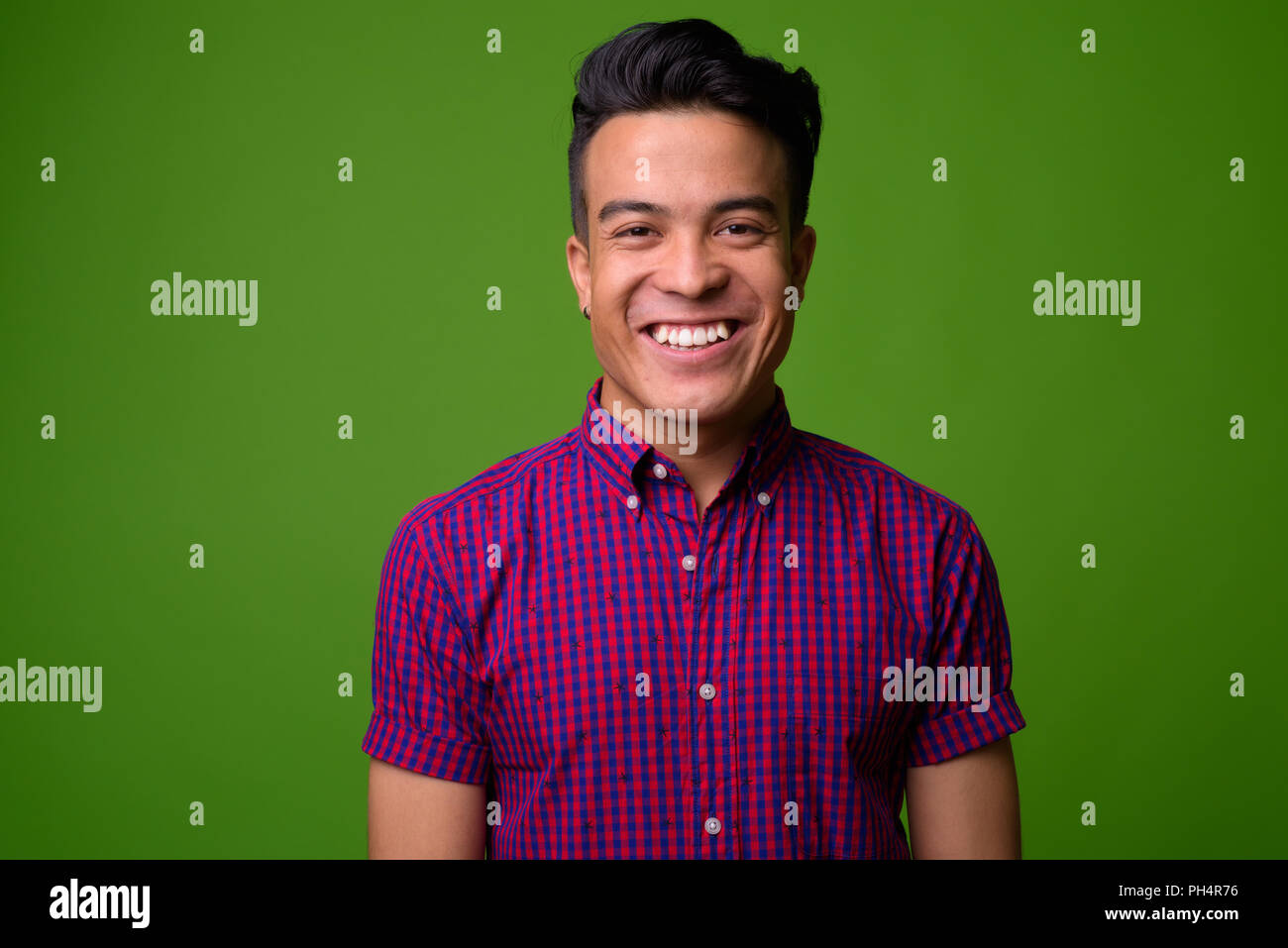 Young multi-ethnic man wearing purple shirt against green background ...