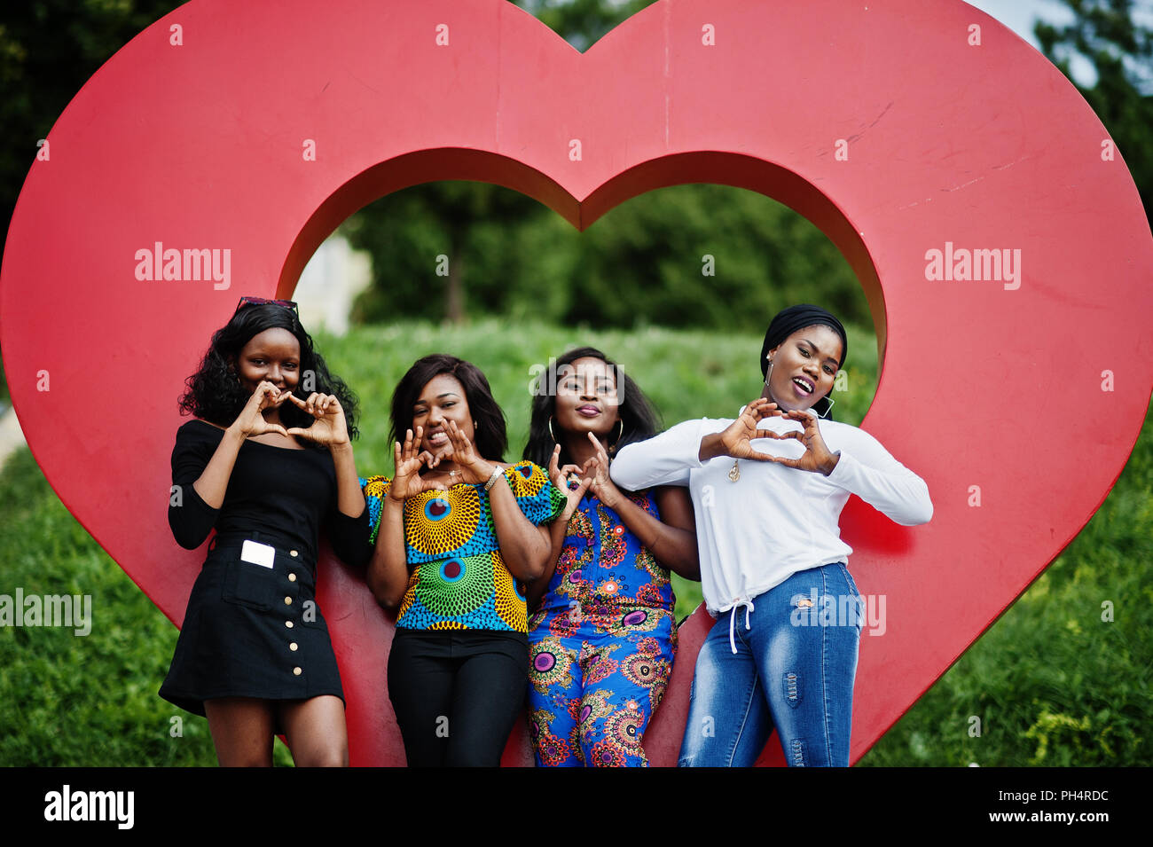 Group of four african american girls against big red heart outdoor ...