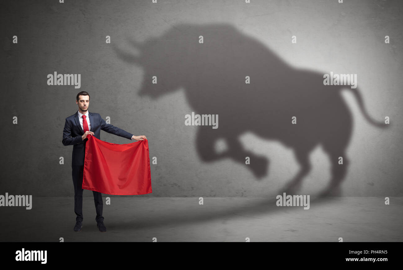 Businessman standing with red cloth in his hand and big bull shadow on ...