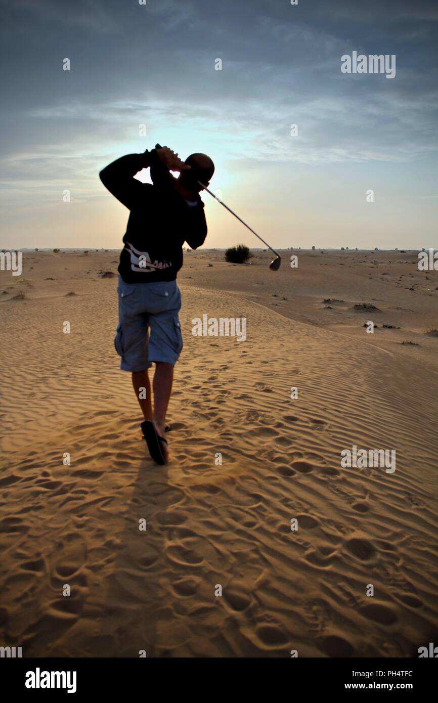 Playing golf in the desert during sunset in Dubai, United Arab Emirates ...