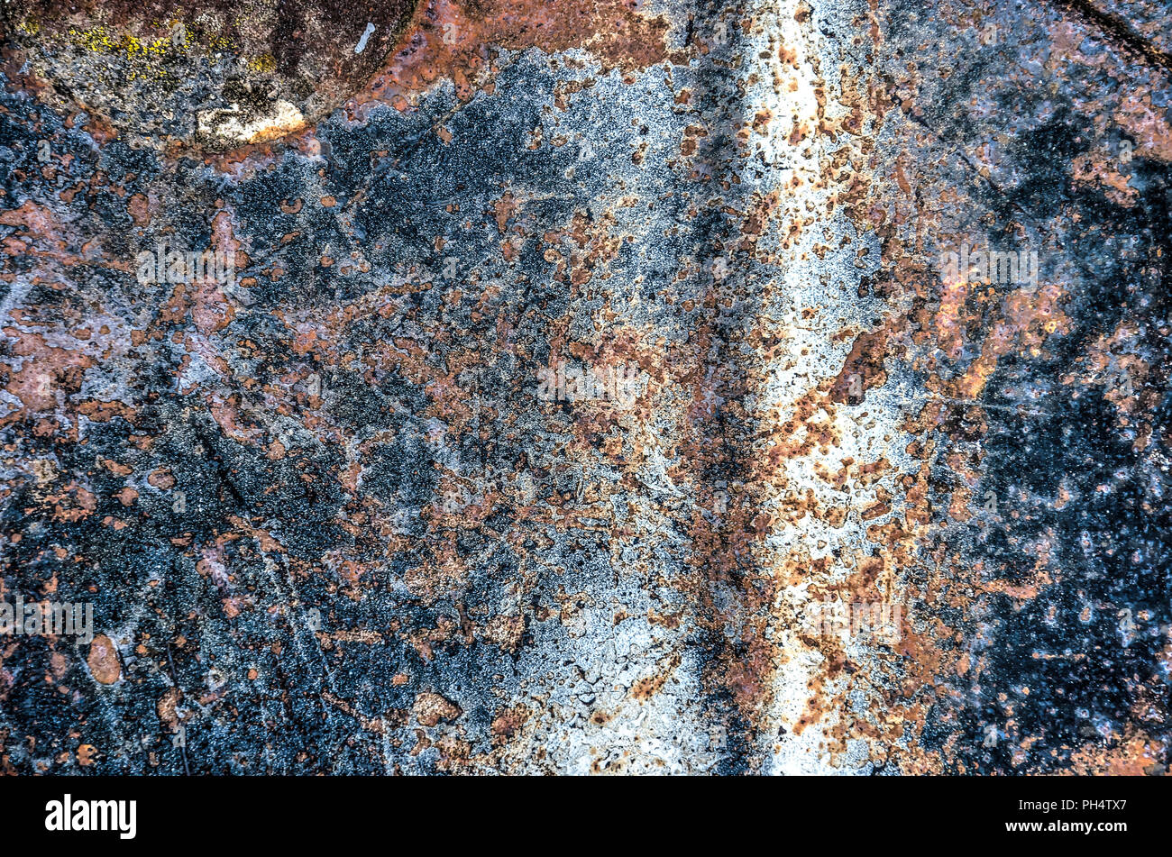 Rough dark steel surface with patches of rust and white paint and other ...