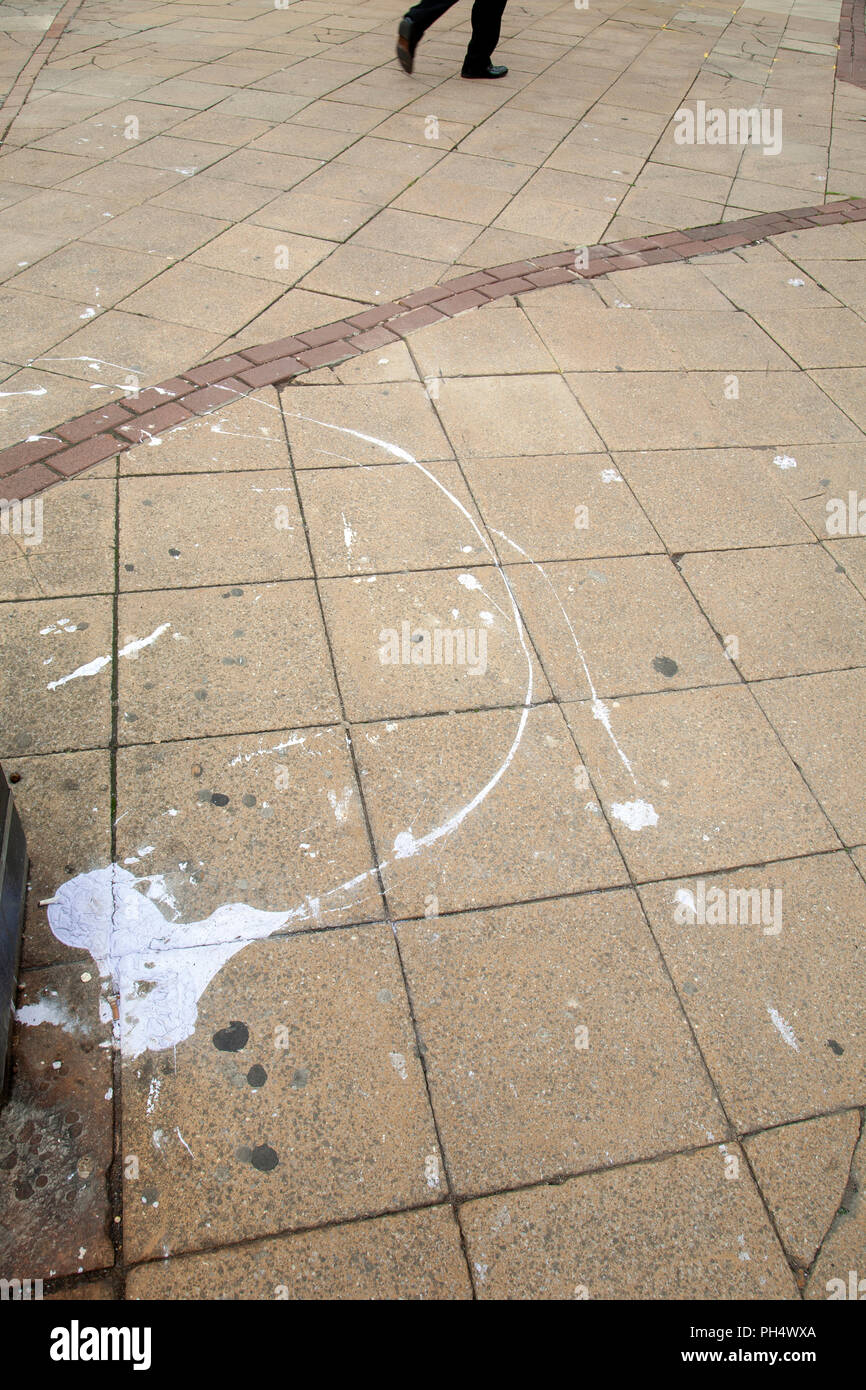 cropped picture of guys legs walking past spilled paint on a pavement ...