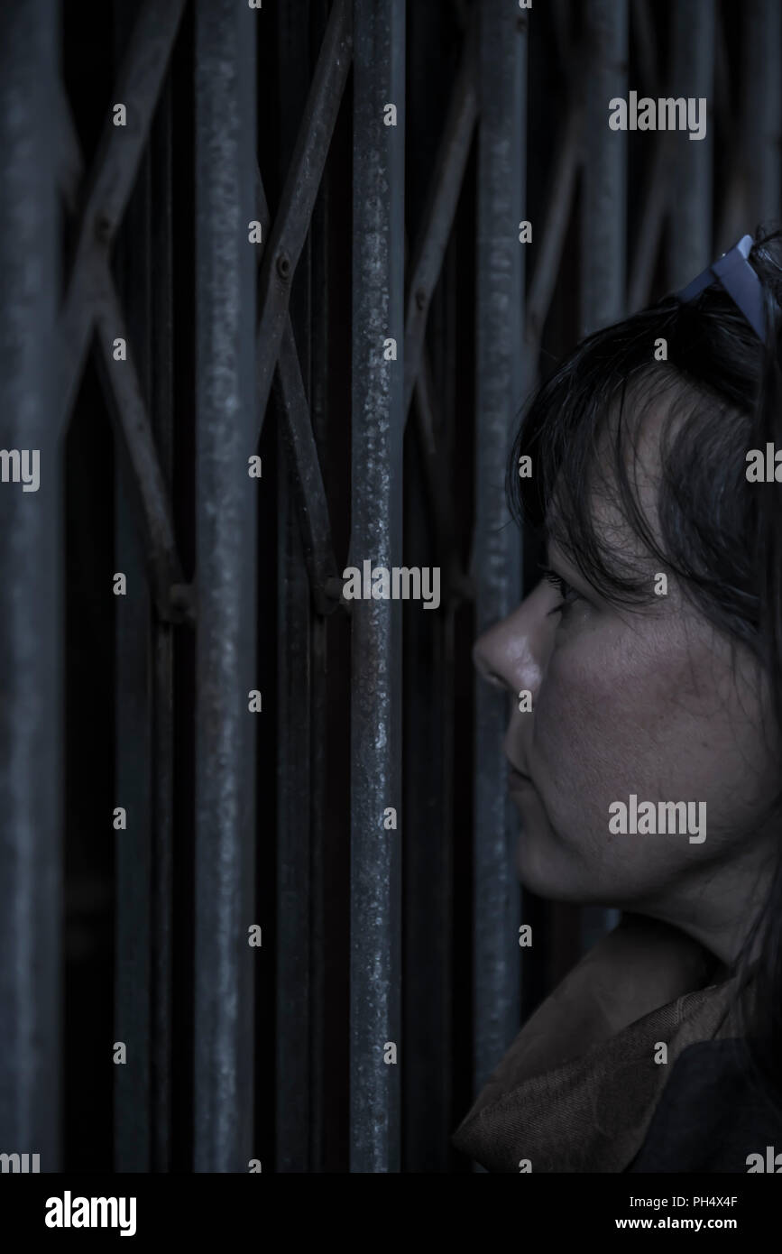 Woman Looking on a Metal Gate Stock Photo - Alamy