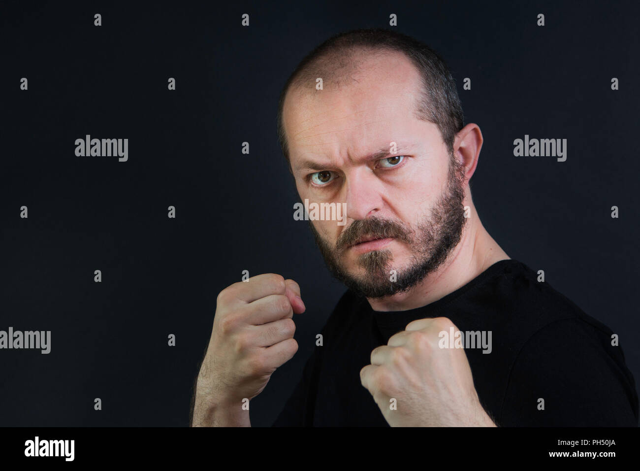 Serious aggressive man with beard and mustaches on black background in ...