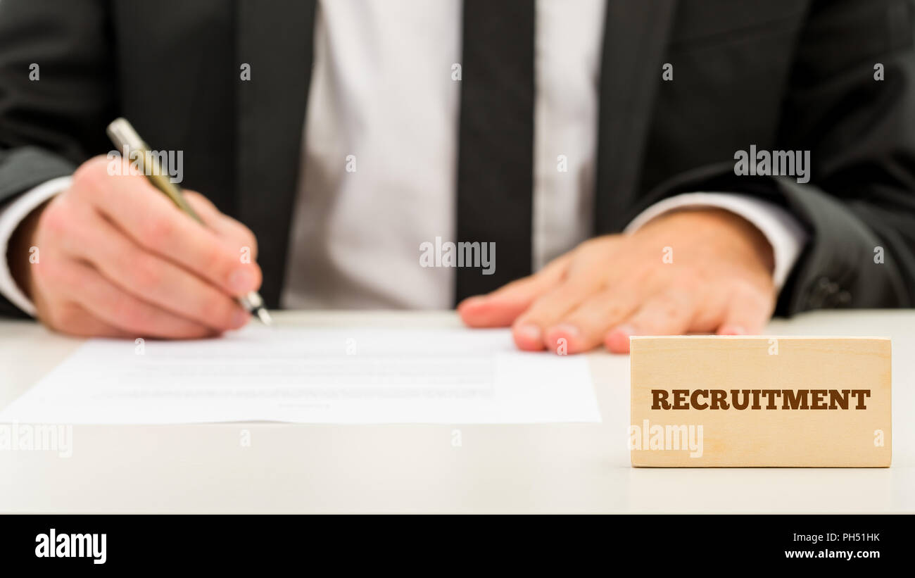 Applicant completing a job application with a small wooden block in the ...