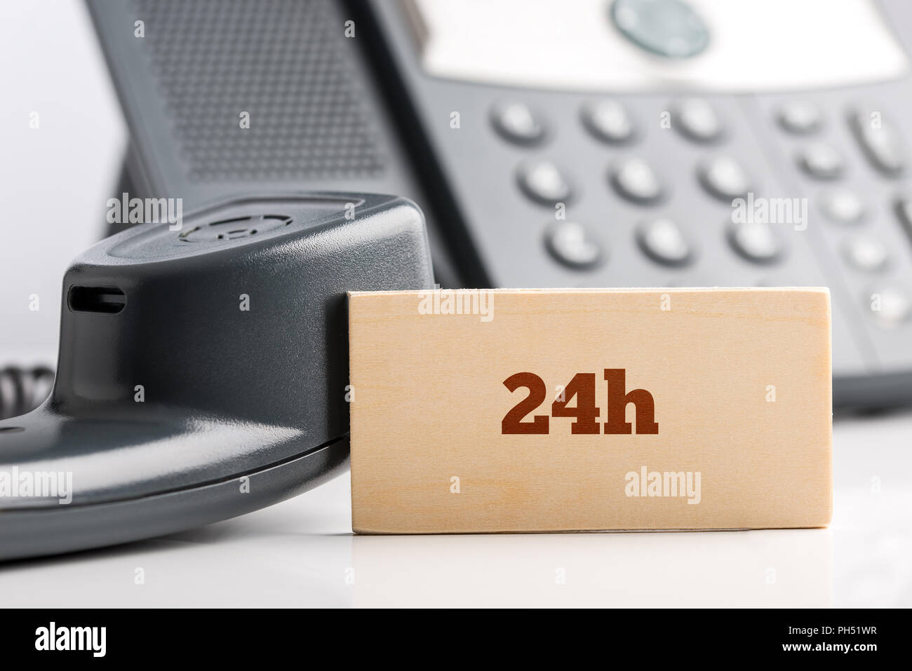 24h business telephone support concept with a small wooden sign saying ...