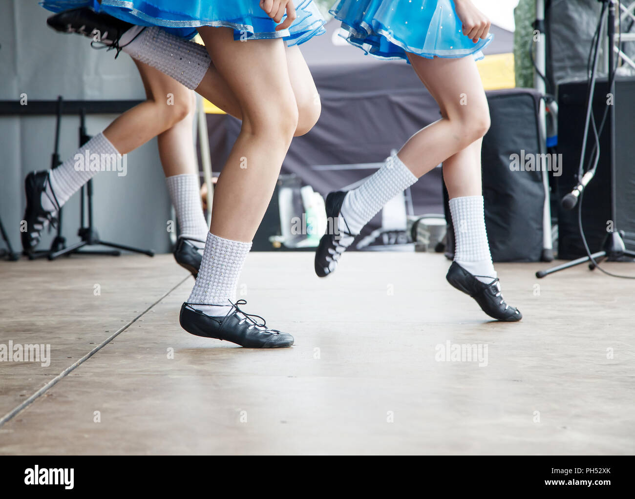 female legs of three irish dancers in blue dresses on the stage closeup ...