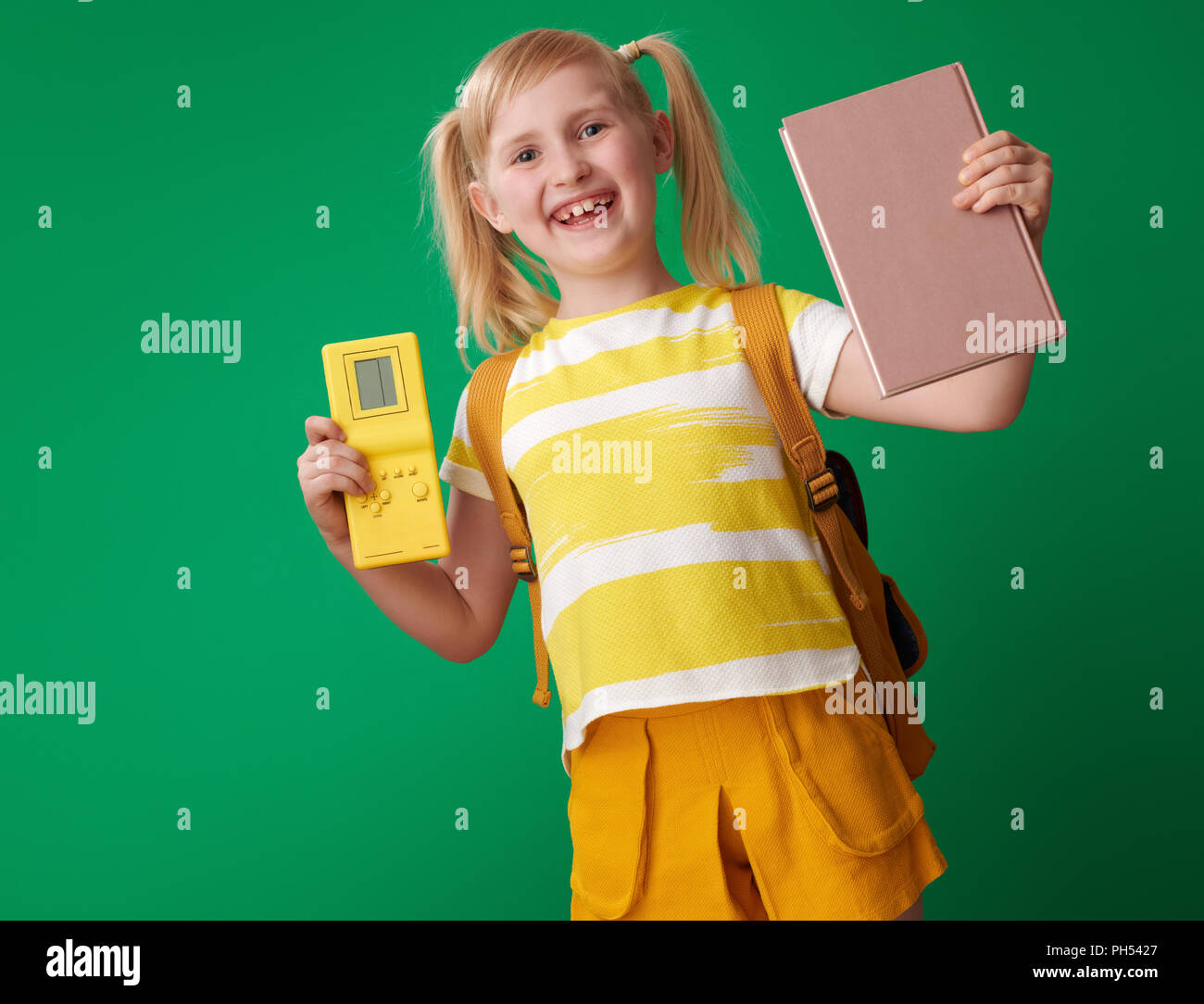 happy school girl with backpack chosen book instead of video game on ...
