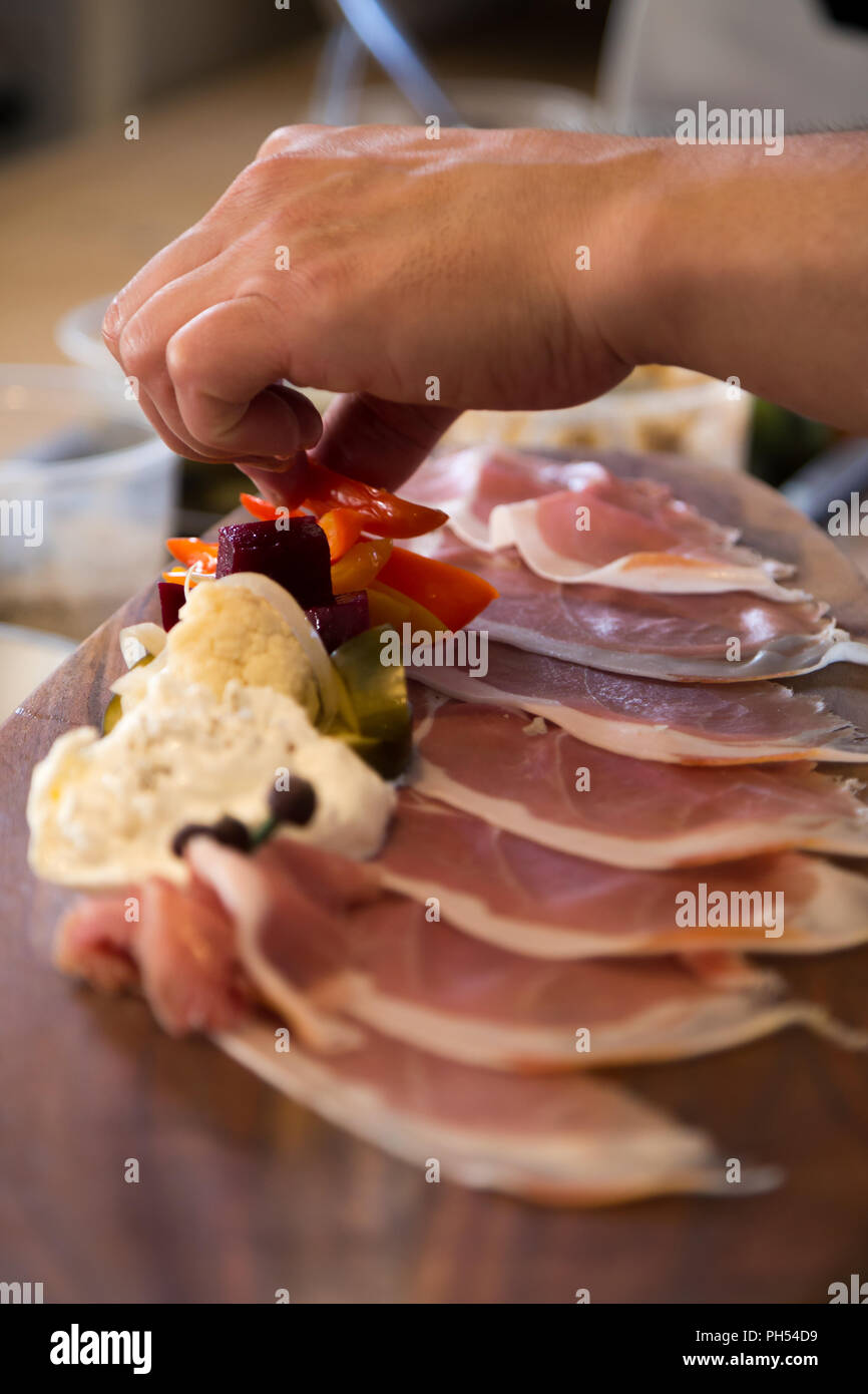 Hand plating appetizers on a wooden board with proscuitto Stock Photo ...