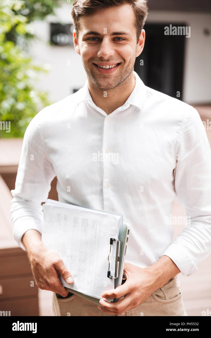 Attractive young male manager formal dressed holding notepad, walking ...