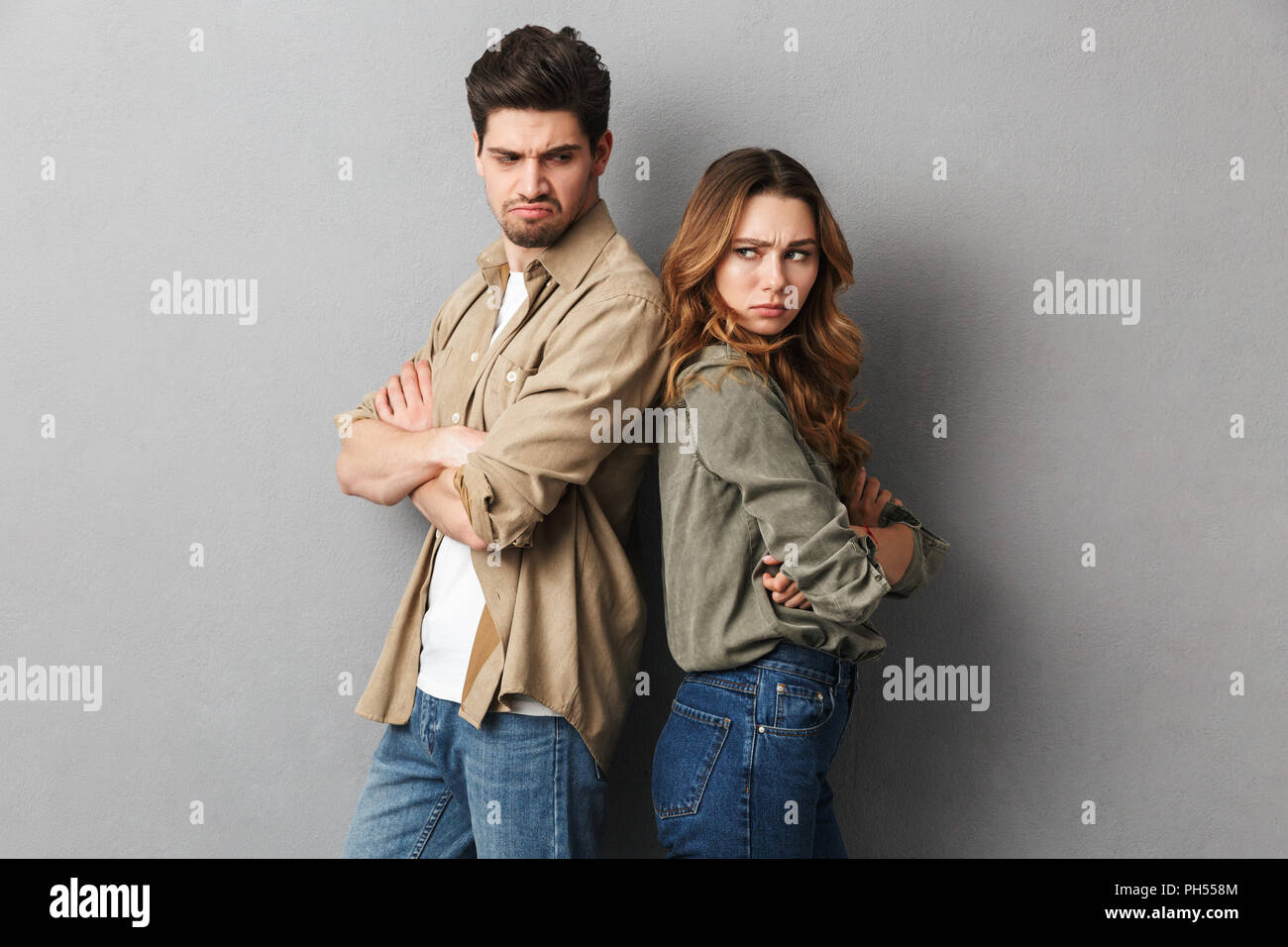 Portrait of an upset young couple having an argument isolated over gray ...