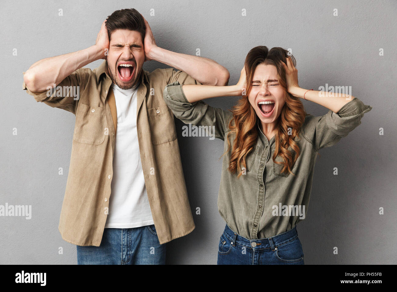 Portrait of a shocked young couple screaming loud isolated over gray ...