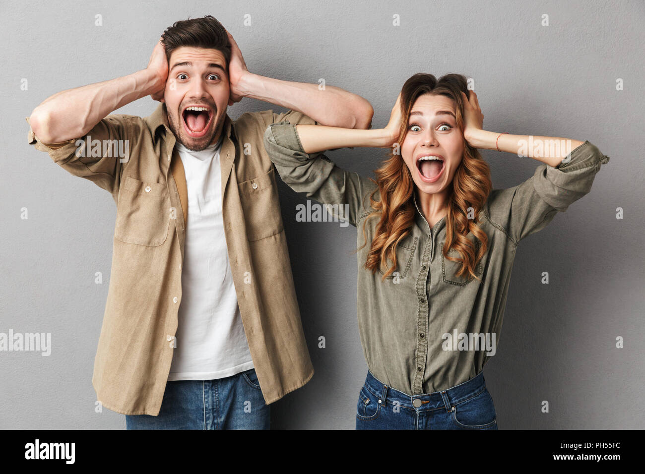 Portrait of a happy young couple screaming loud isolated over gray ...