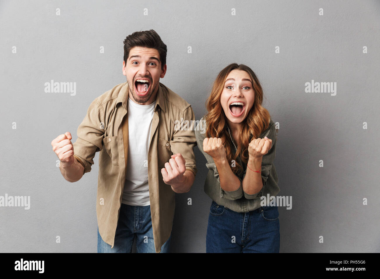 Portrait of a happy young couple screaming and celebrating success ...