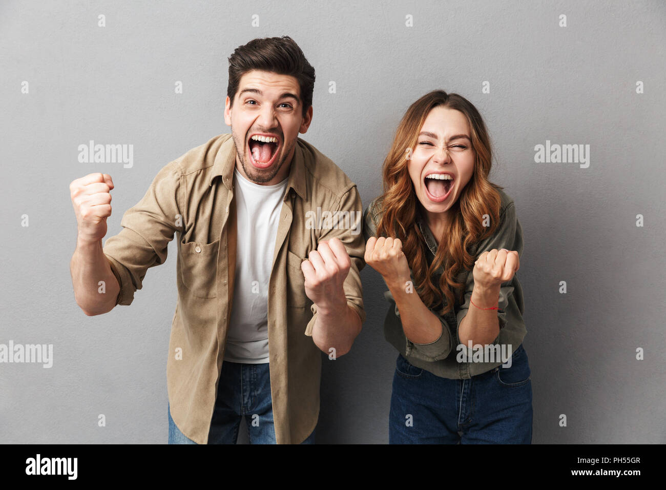 Portrait of a cheerful young couple screaming and celebrating success ...