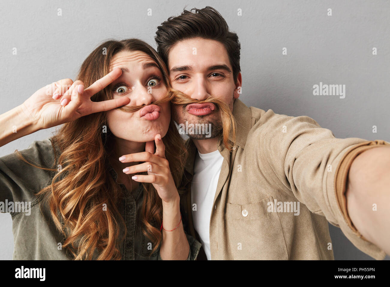 Portrait of a happy young couple hugging while taking a selfie and ...