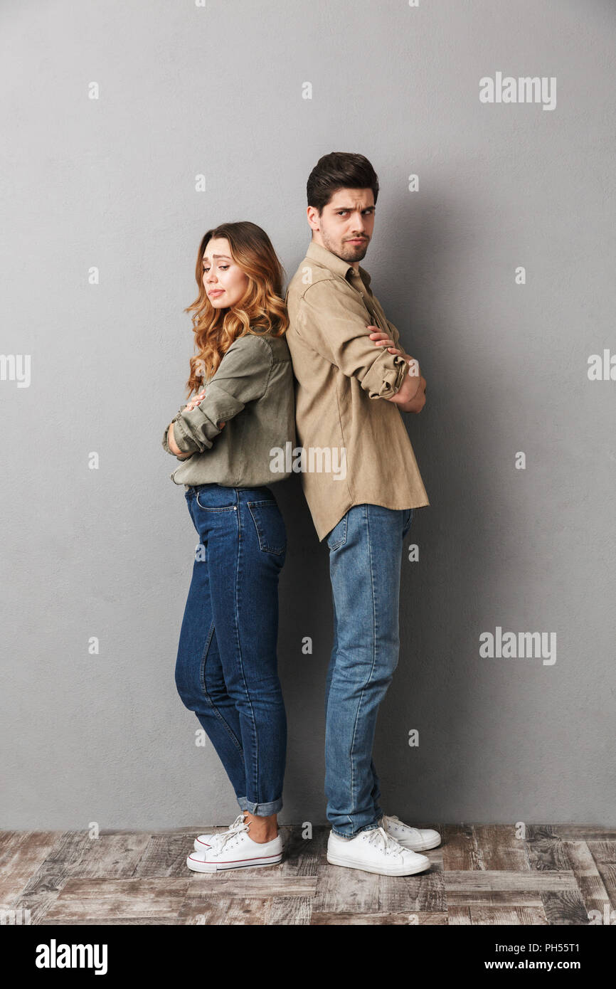Full length portrait of an upset young couple standing back to back ...