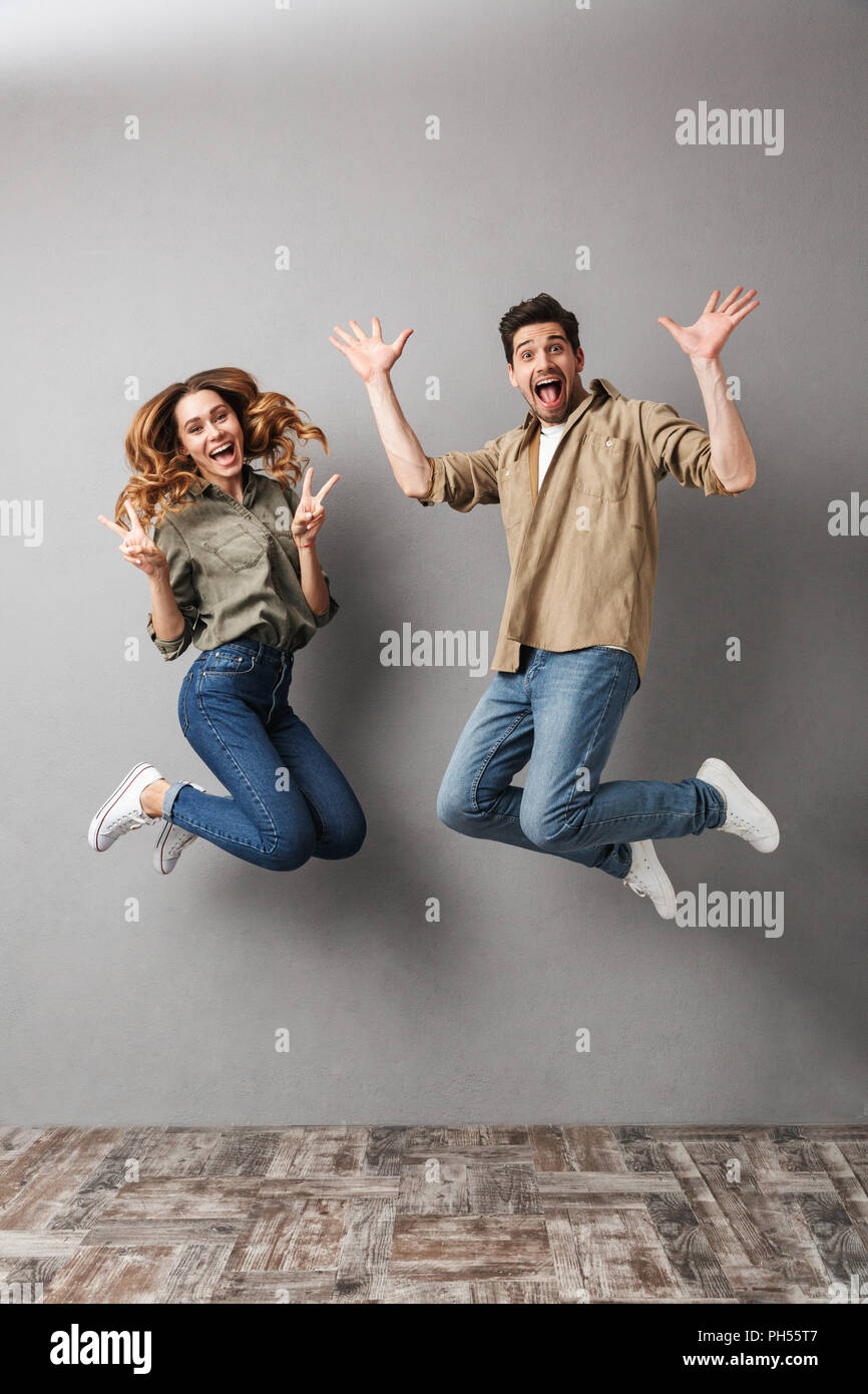 Full length portrait of a cheerful young couple jumping together and ...