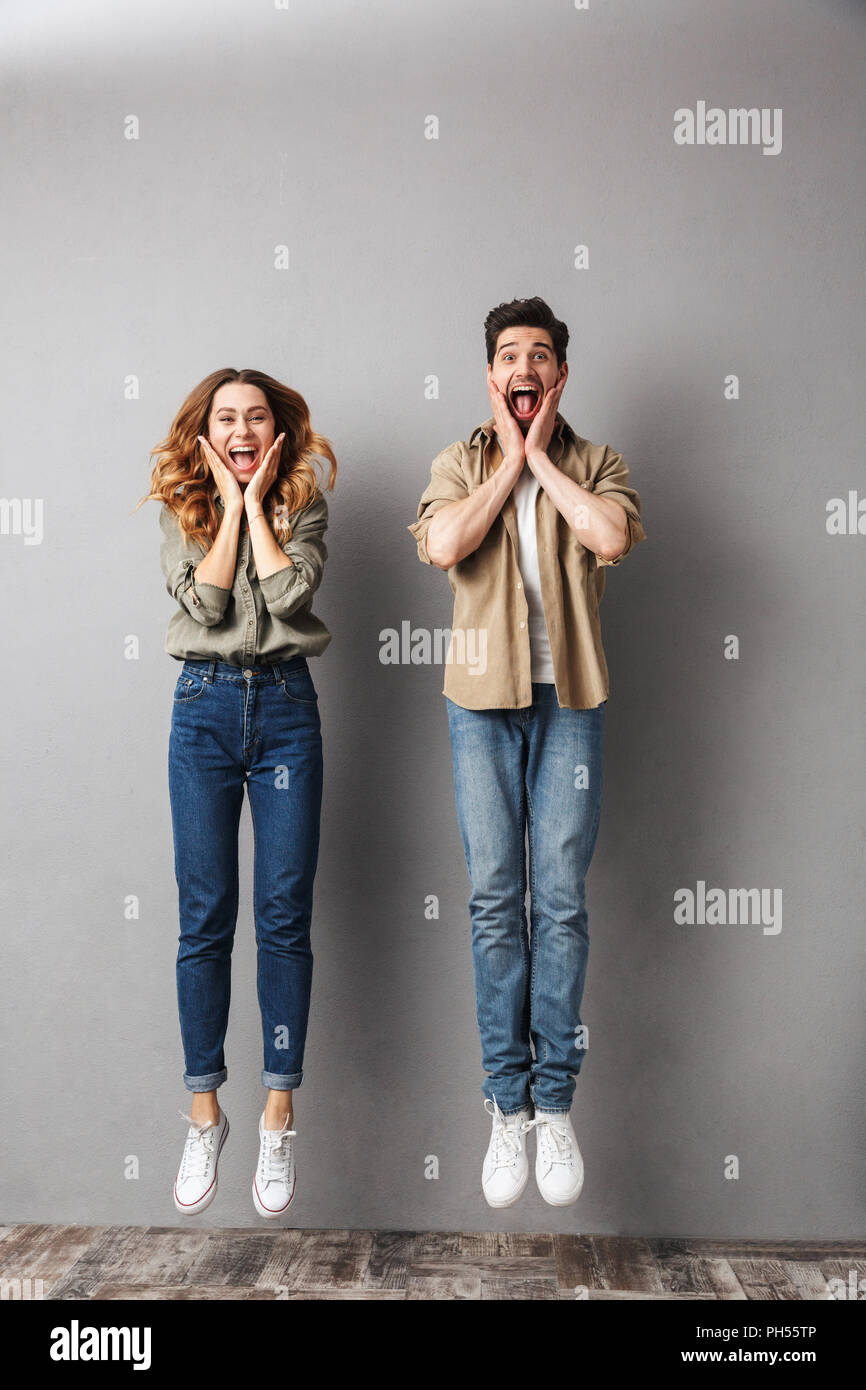 Full length portrait of an excited young couple jumping together ...