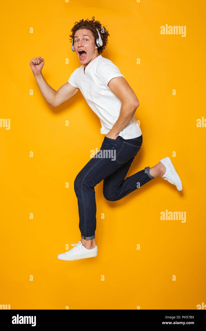 Full length photo of young excited guy with curly hair running or ...