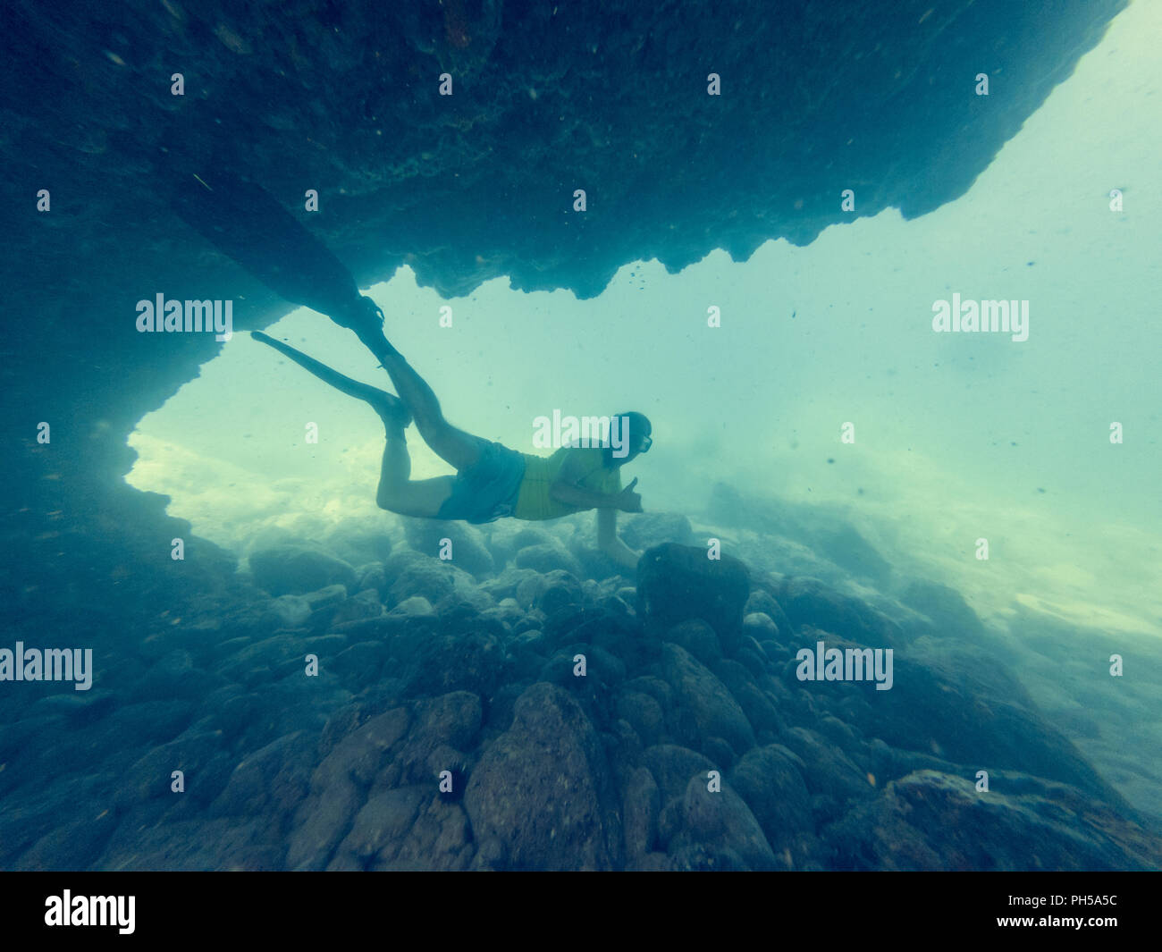 Male diver swimming through natural underwater tunnel Stock Photo - Alamy