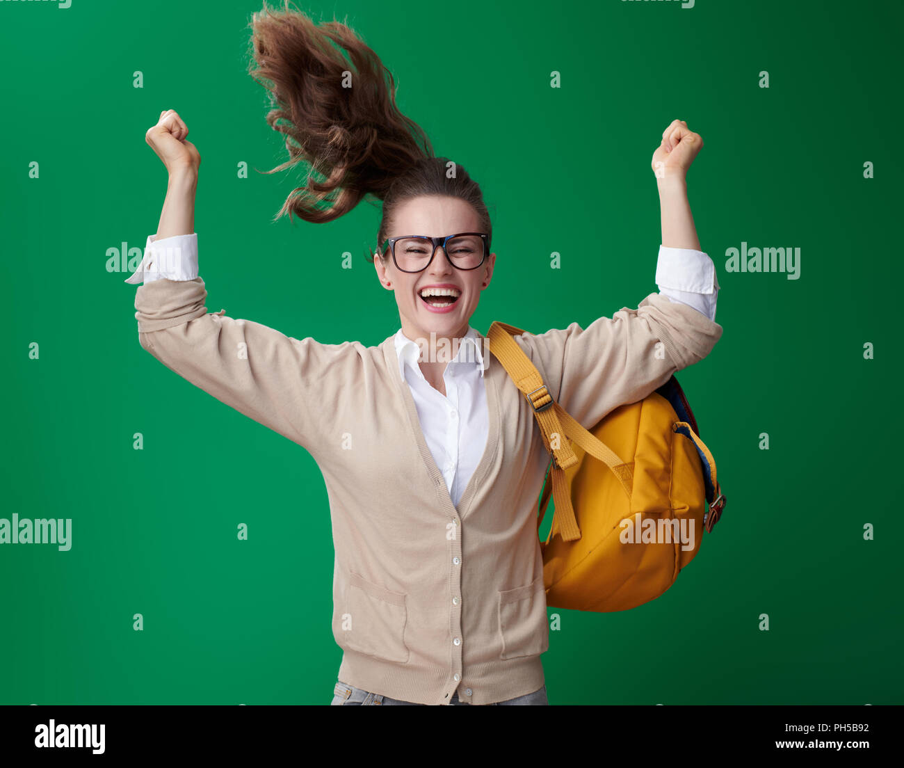 smiling modern student woman jumping and rejoicing isolated on green ...