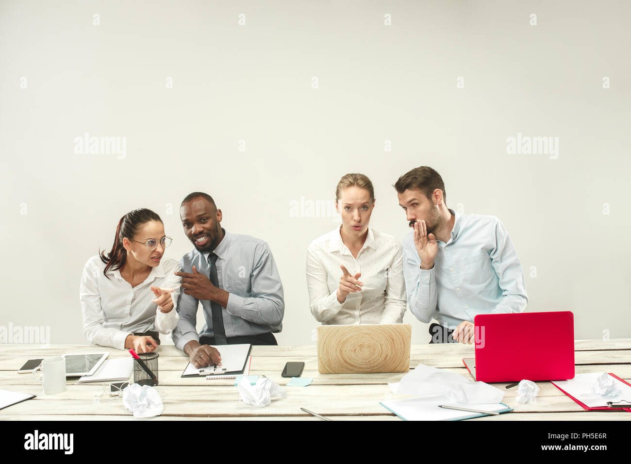 gossip. Young african and caucasian men and women sitting at office and ...