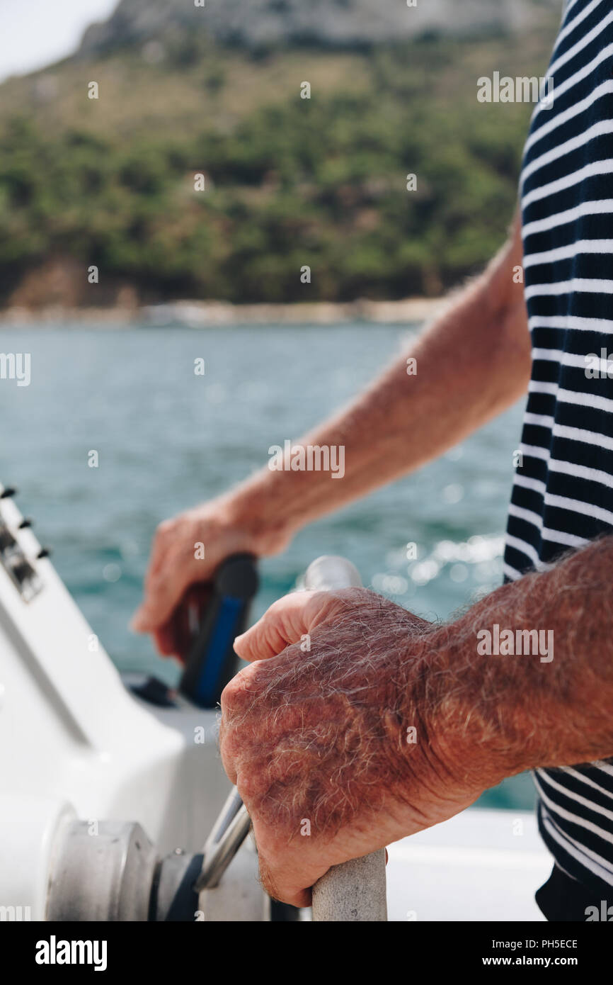 Close-up of Hand of Senior Captain on steering wheel of motor boat ...