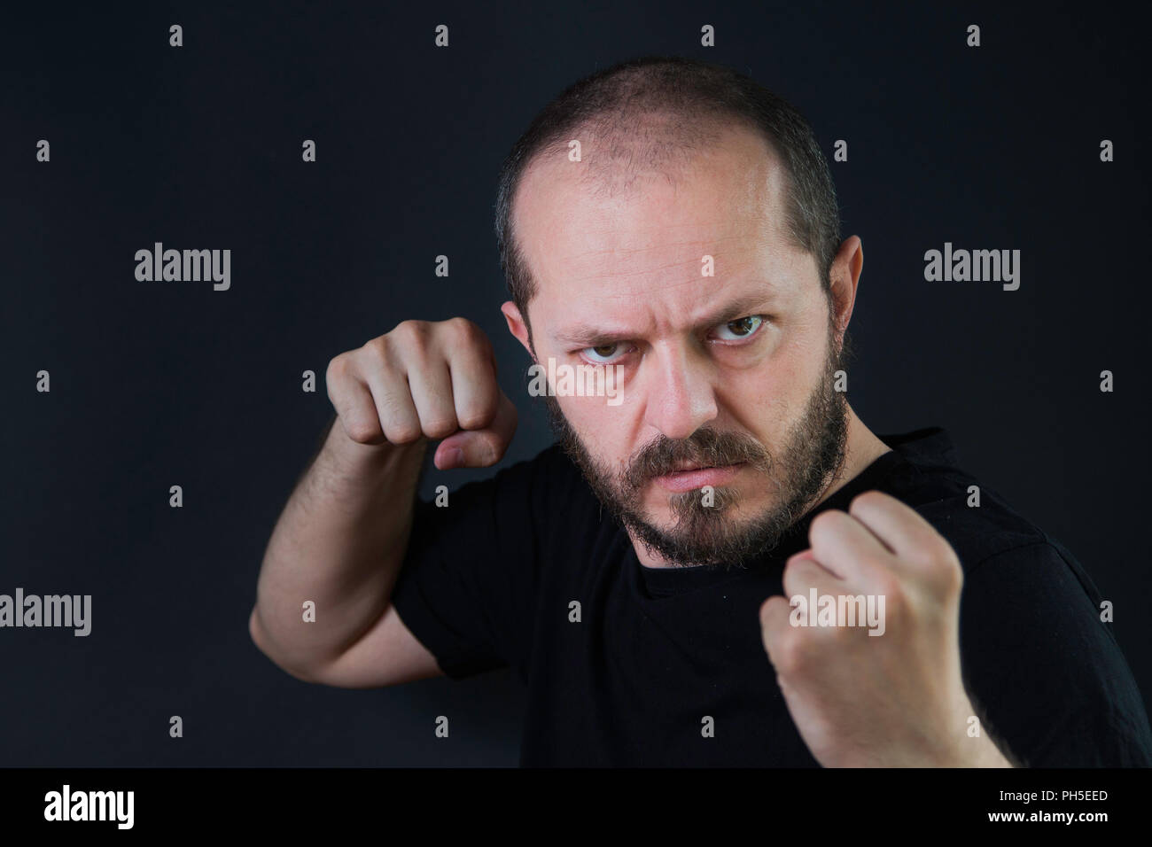 Serious aggressive man with beard and mustaches on black background in ...