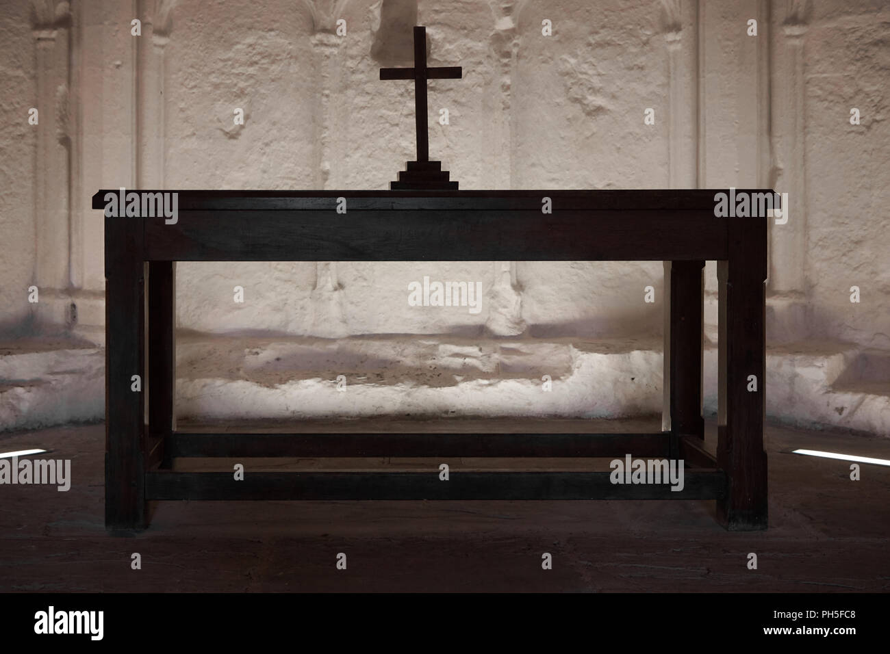 Cross on the table against a white wall Stock Photo - Alamy