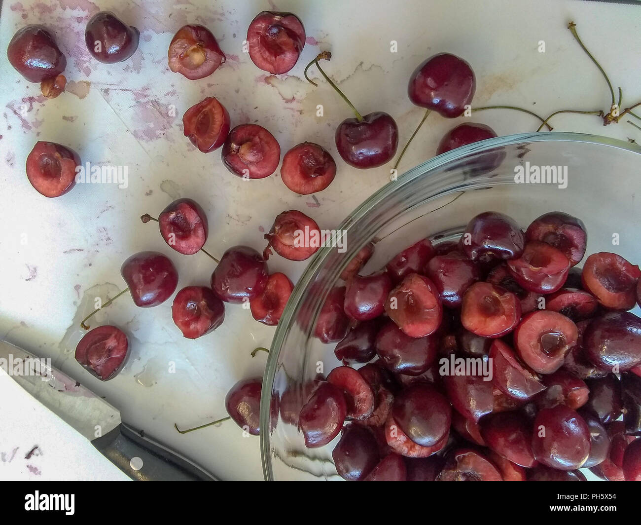 fresh red cherries cut into halves on white cutting board kitchen still ...