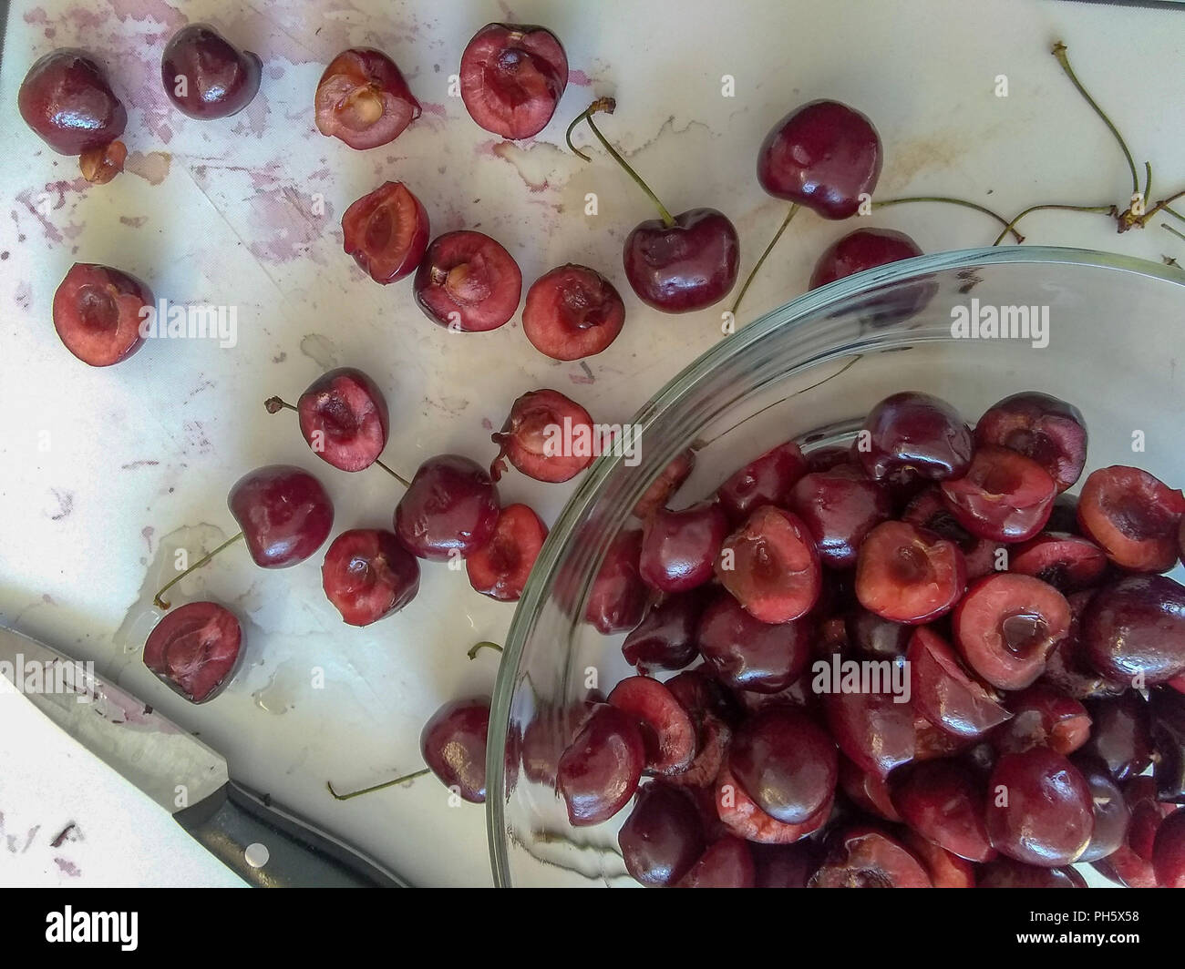 fresh red cherries cut into halves on white cutting board kitchen still ...