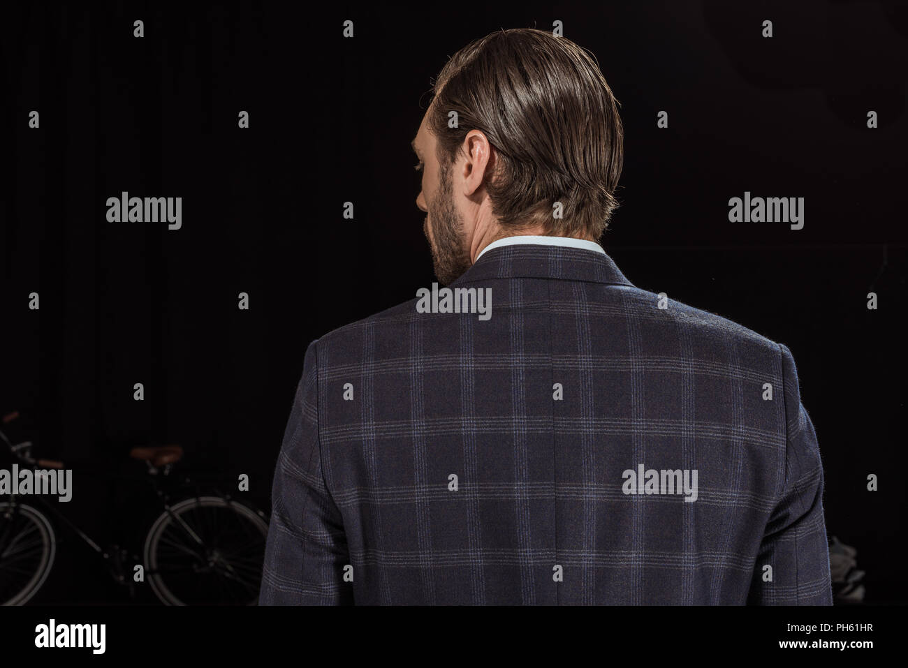back view of stylish young man and bicycle on black Stock Photo - Alamy