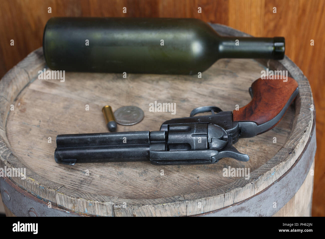Old western revolver with cartridges and silver dollar on wooden barrel ...
