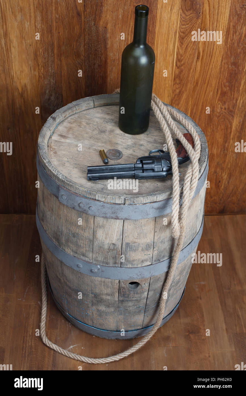 Old western revolver with cartridges and silver dollar on wooden barrel ...