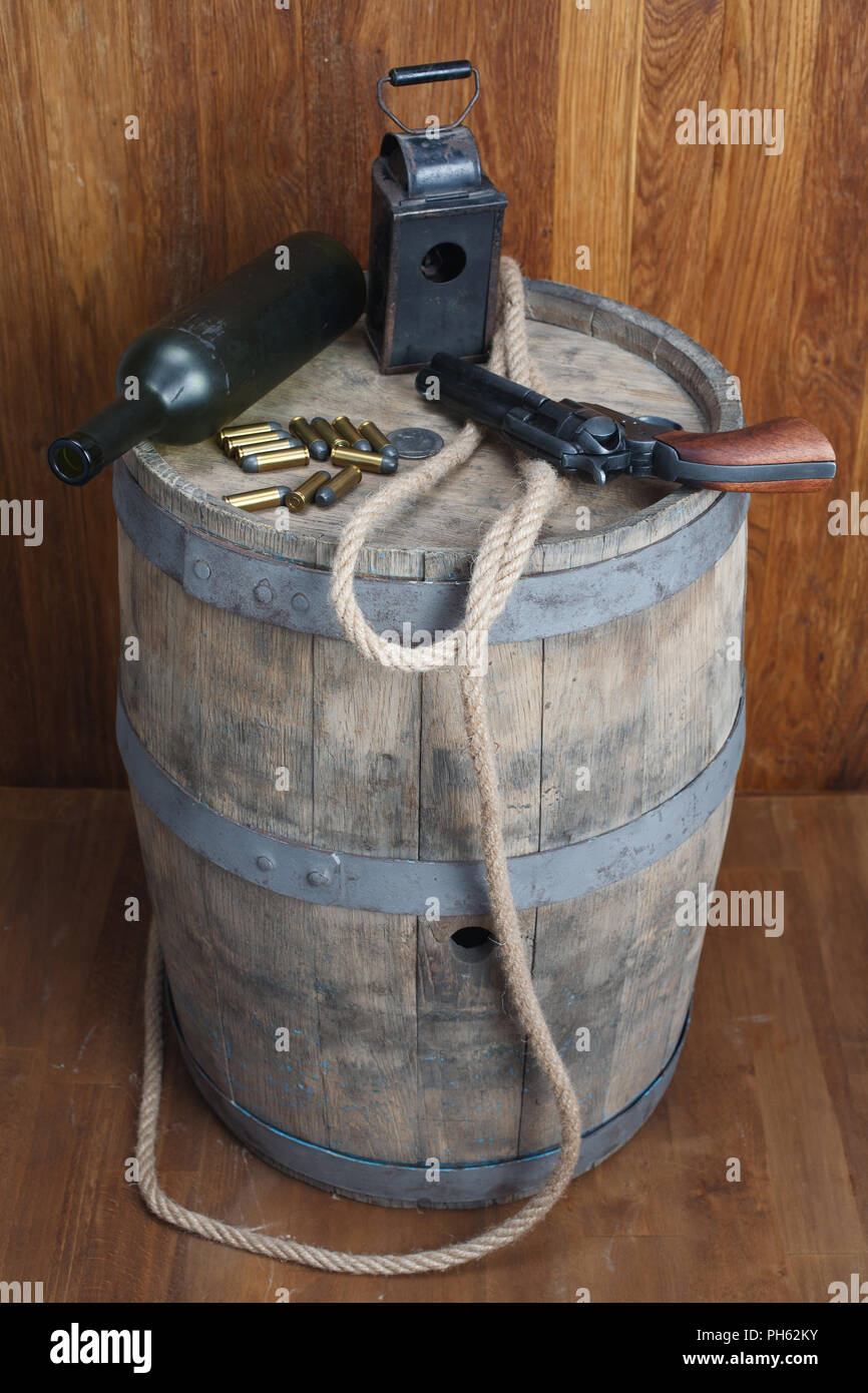 Old western revolver with cartridges and silver dollar on wooden barrel ...