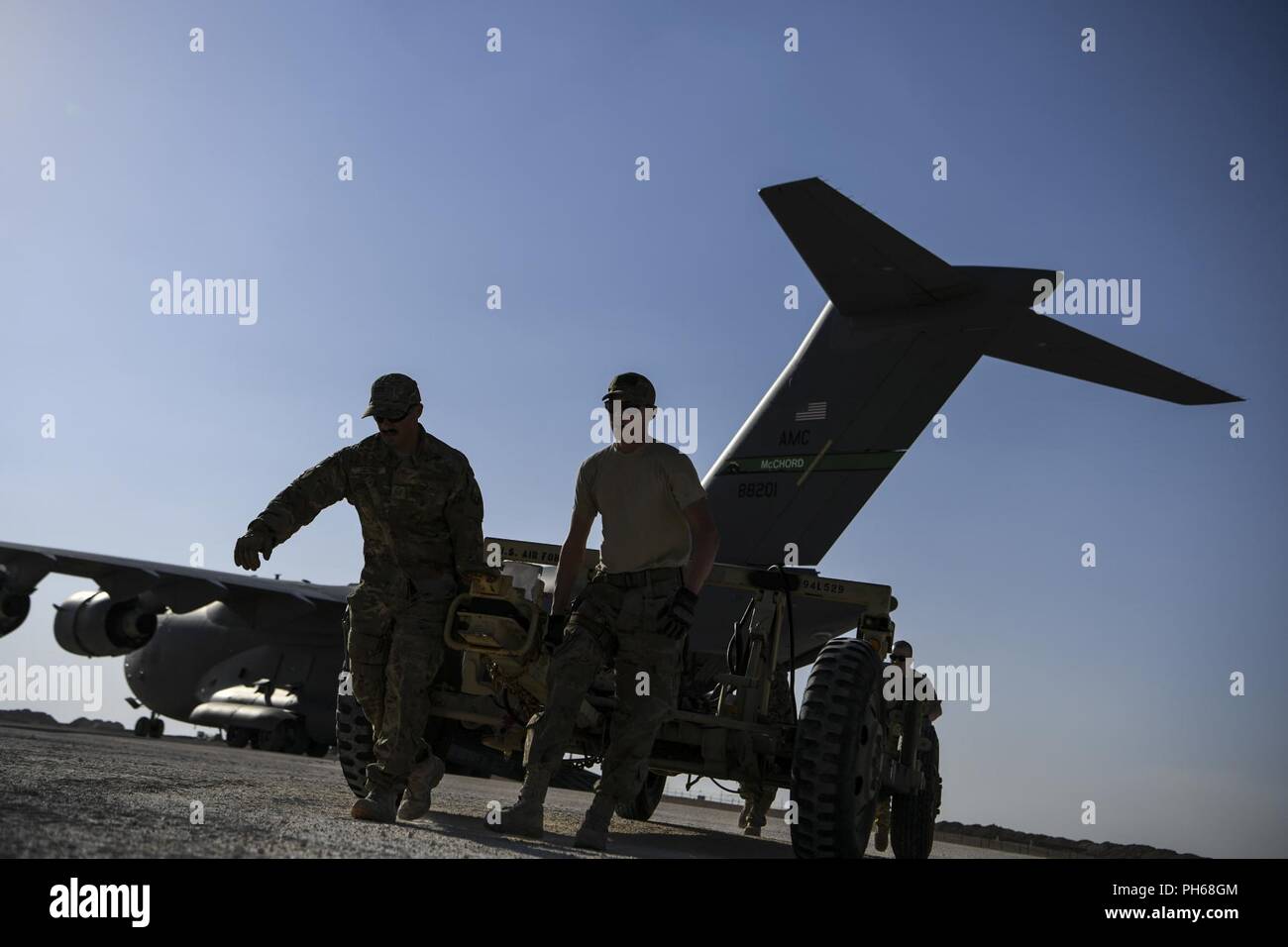 U.S. Army and U.S. Air Force aerial porters roll a utility trailer off ...