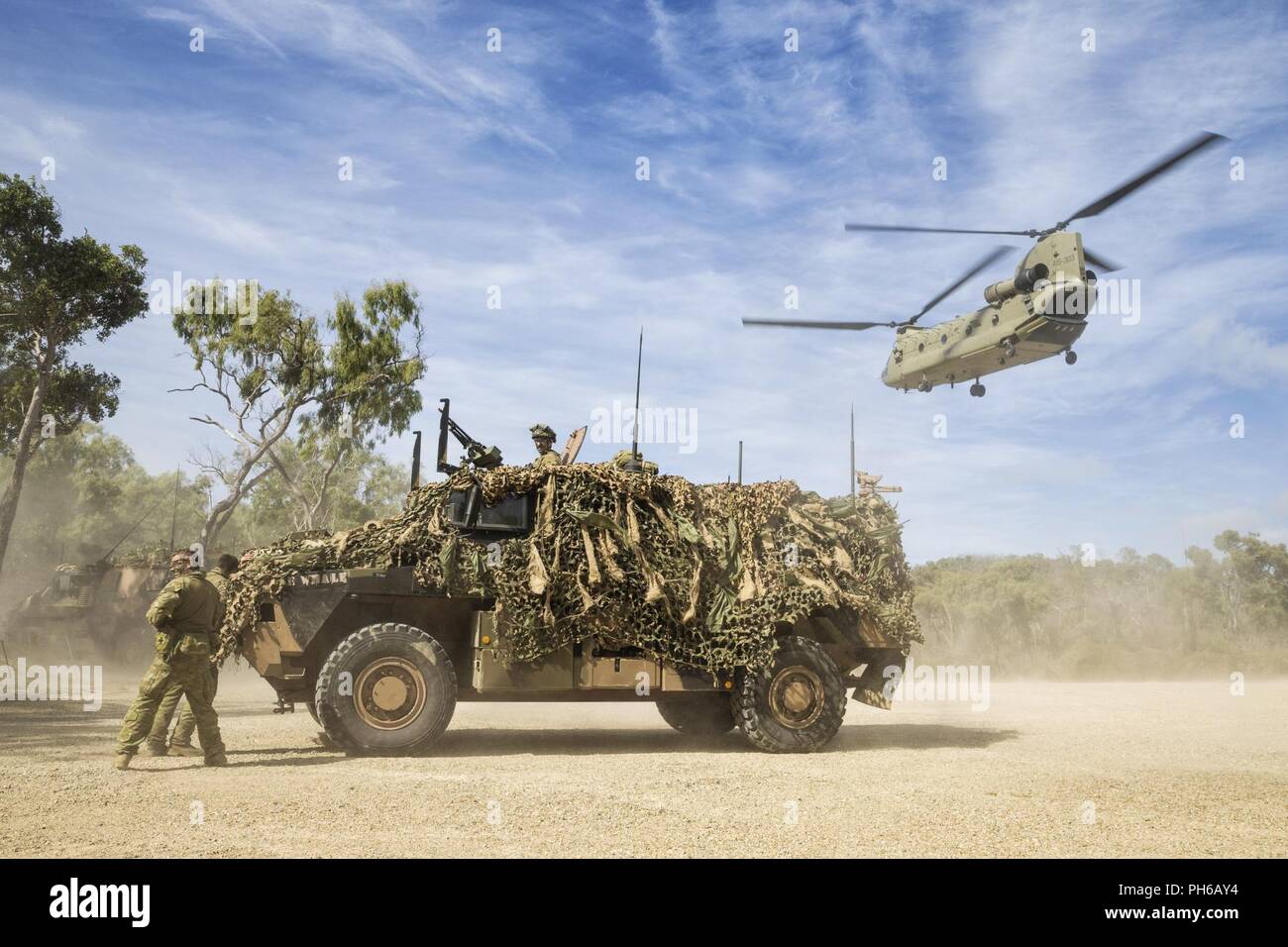 Soldiers take cover behind a Bushmaster Protected Mobility Vehicle as a ...