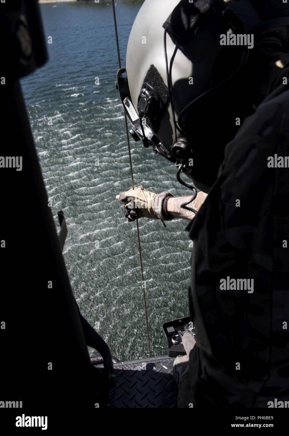 A Pararescueman guides a hoist line while hoisting pararescuemen out of ...