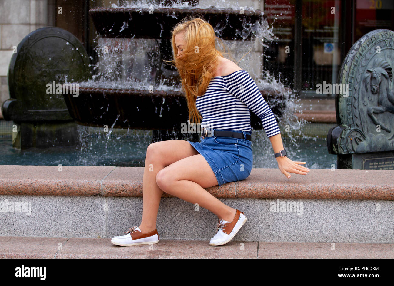 A young woman (Rhianna Martin) sitting beside the City Square fountain ...